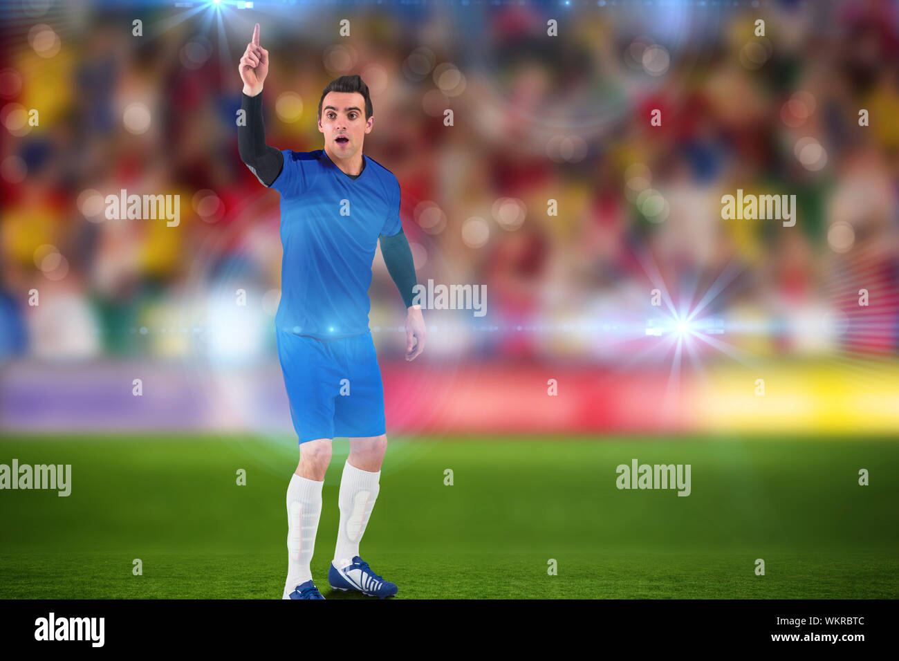Football player raising his hand against blurry football pitch with ...
