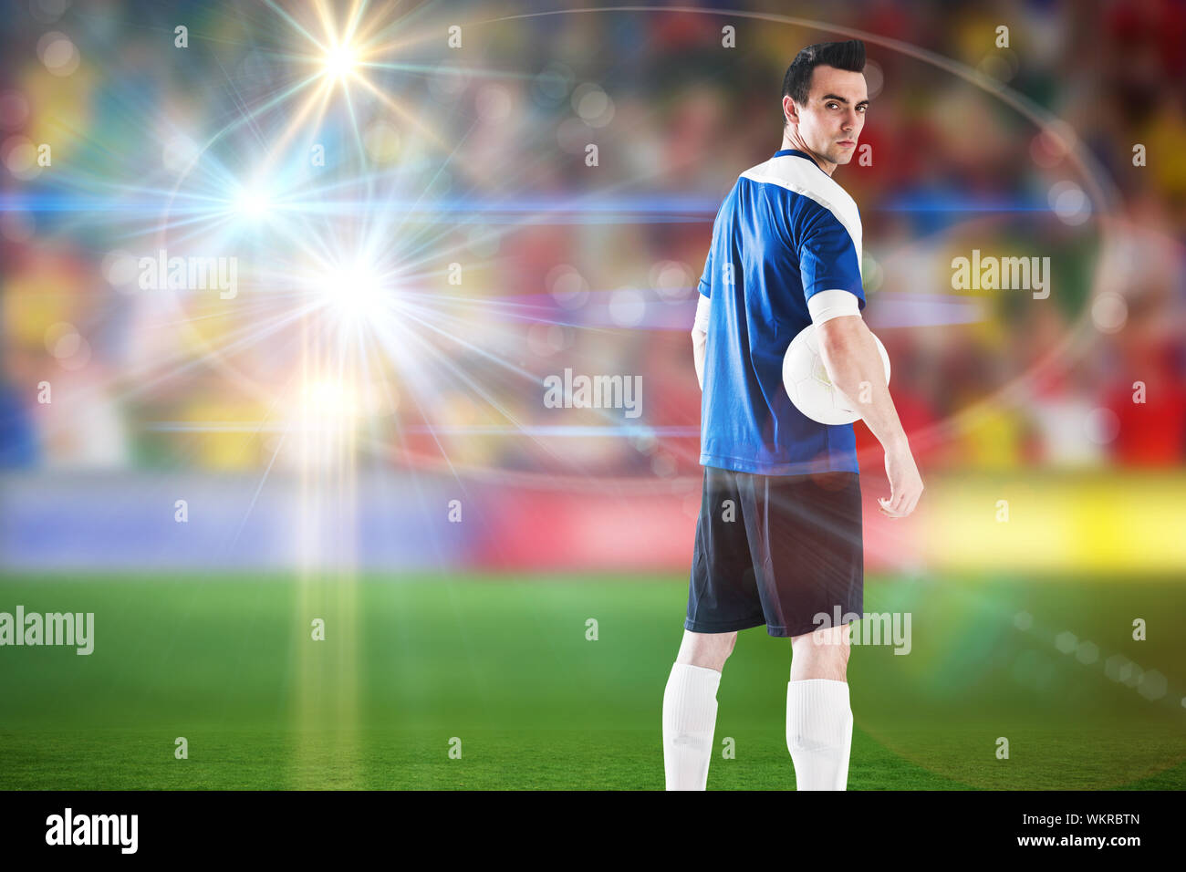 Handsome football player in blue jersey against blurry football pitch ...