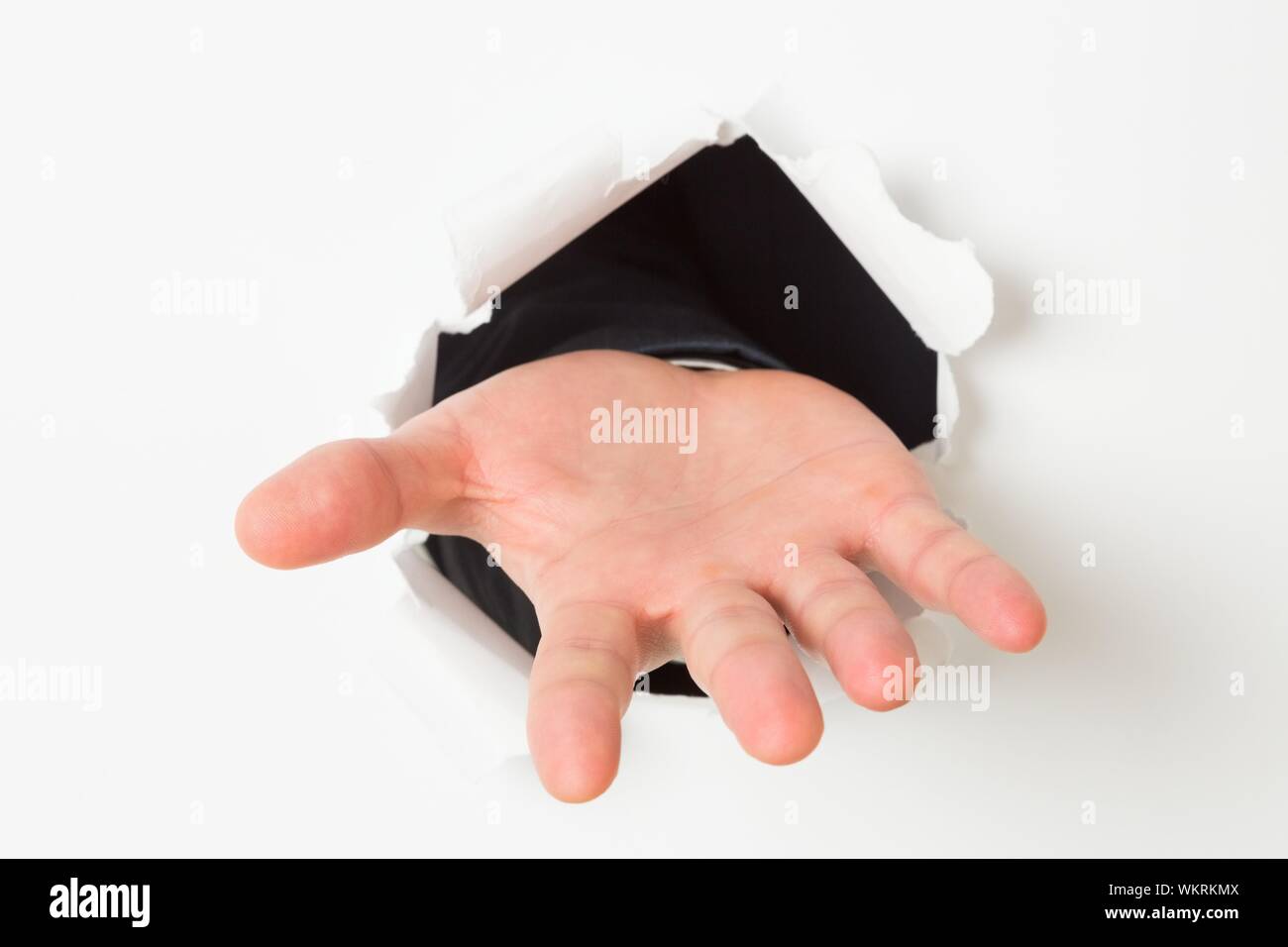 Open hand bursting through paper on white background Stock Photo - Alamy