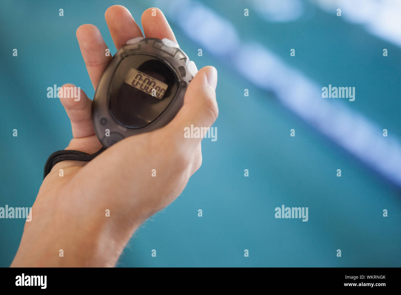 Swimming coach looking at his stopwatch by the pool at the leisure ...
