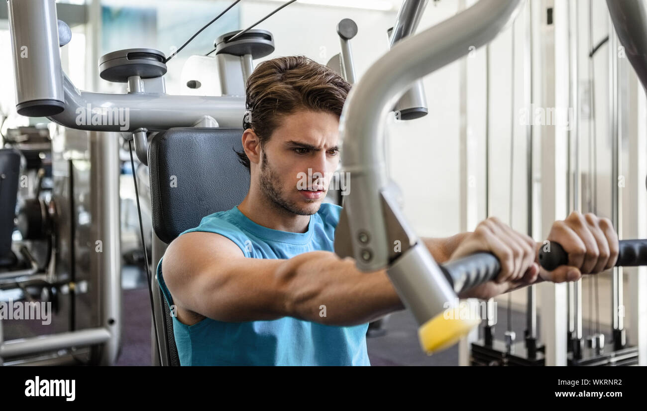 Focused man using weights machine for arms at the gym Stock Photo - Alamy