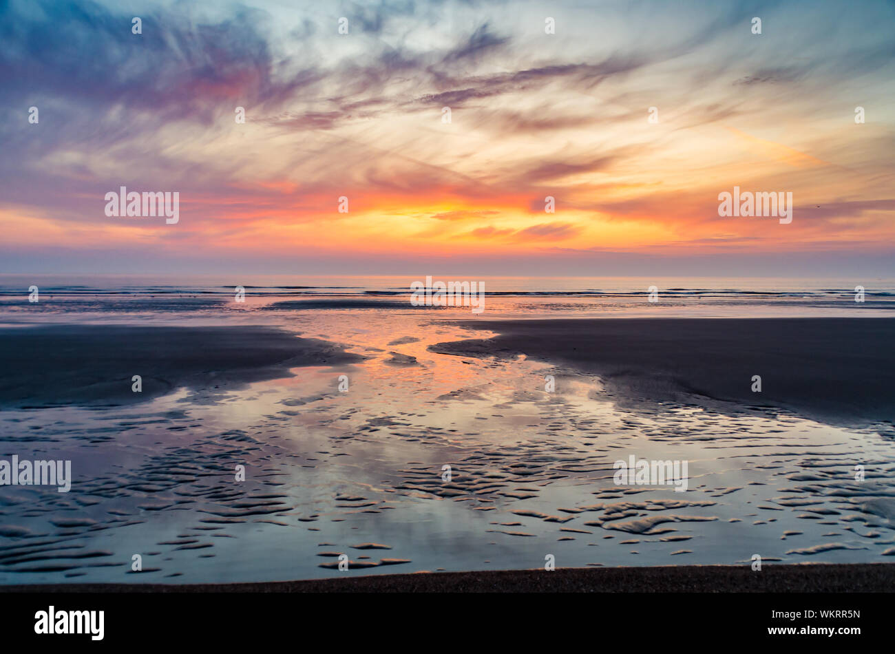 Sunrise at low tide on beach Stock Photo - Alamy