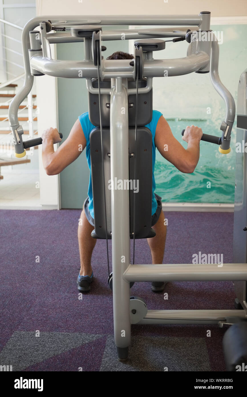 Focused man using weights machine for arms at the gym Stock Photo - Alamy
