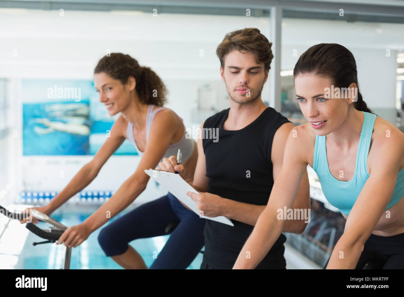 Fit women in a spin class with trainer taking notes at the gym Stock ...