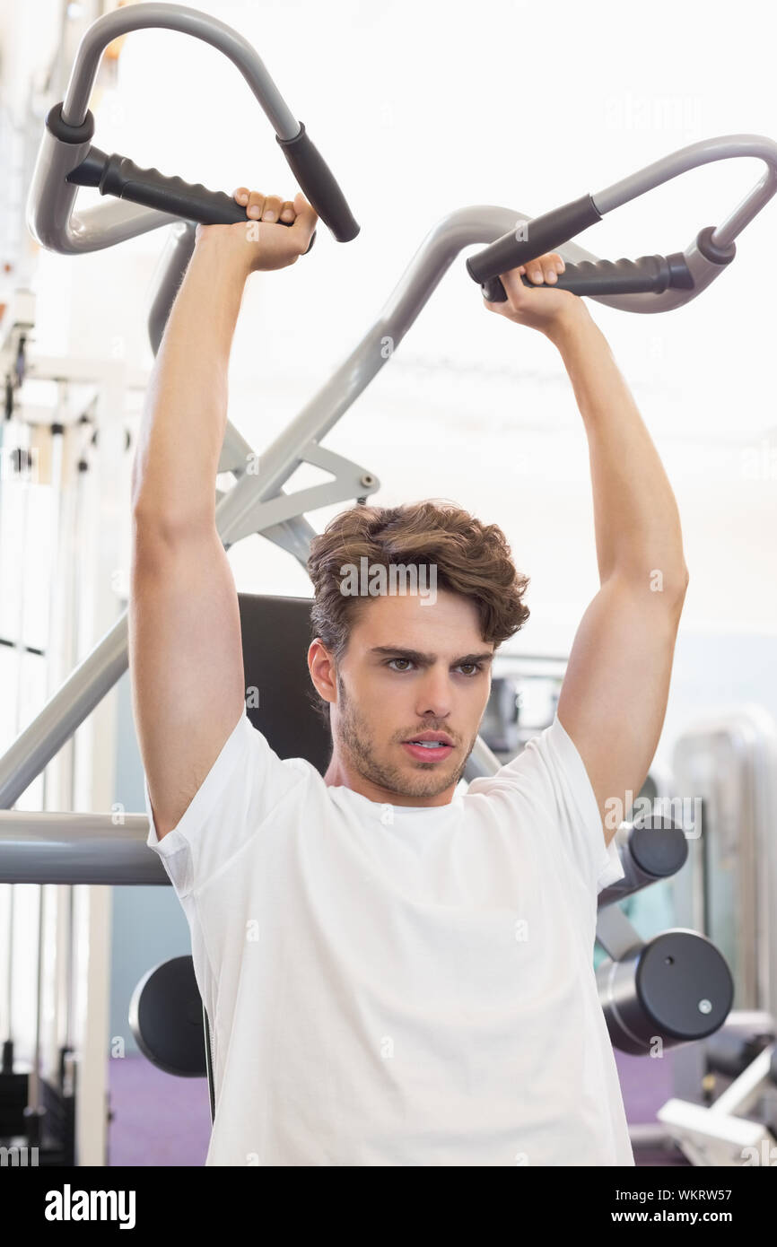 Fit focused man using weights machine for arms at the gym Stock Photo ...