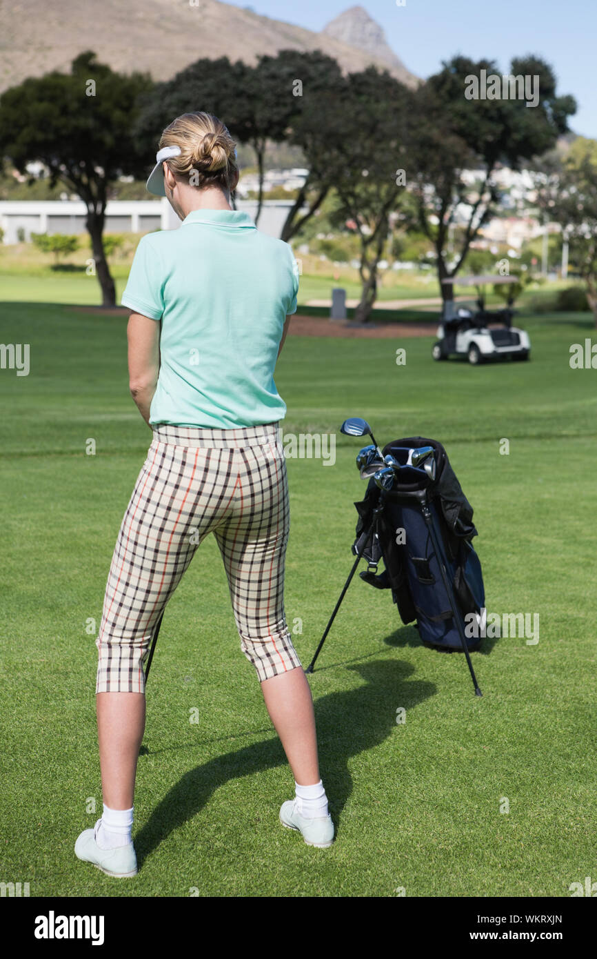 Female concentrating golfer teeing off on a sunny day at the golf ...