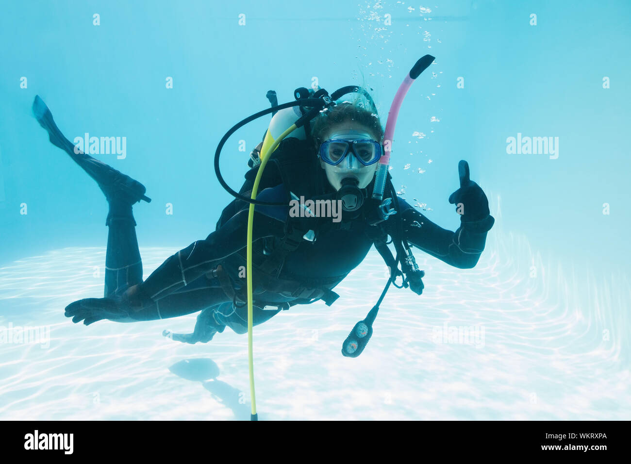 Woman on scuba training submerged in swimming pool showing thumbs up on ...