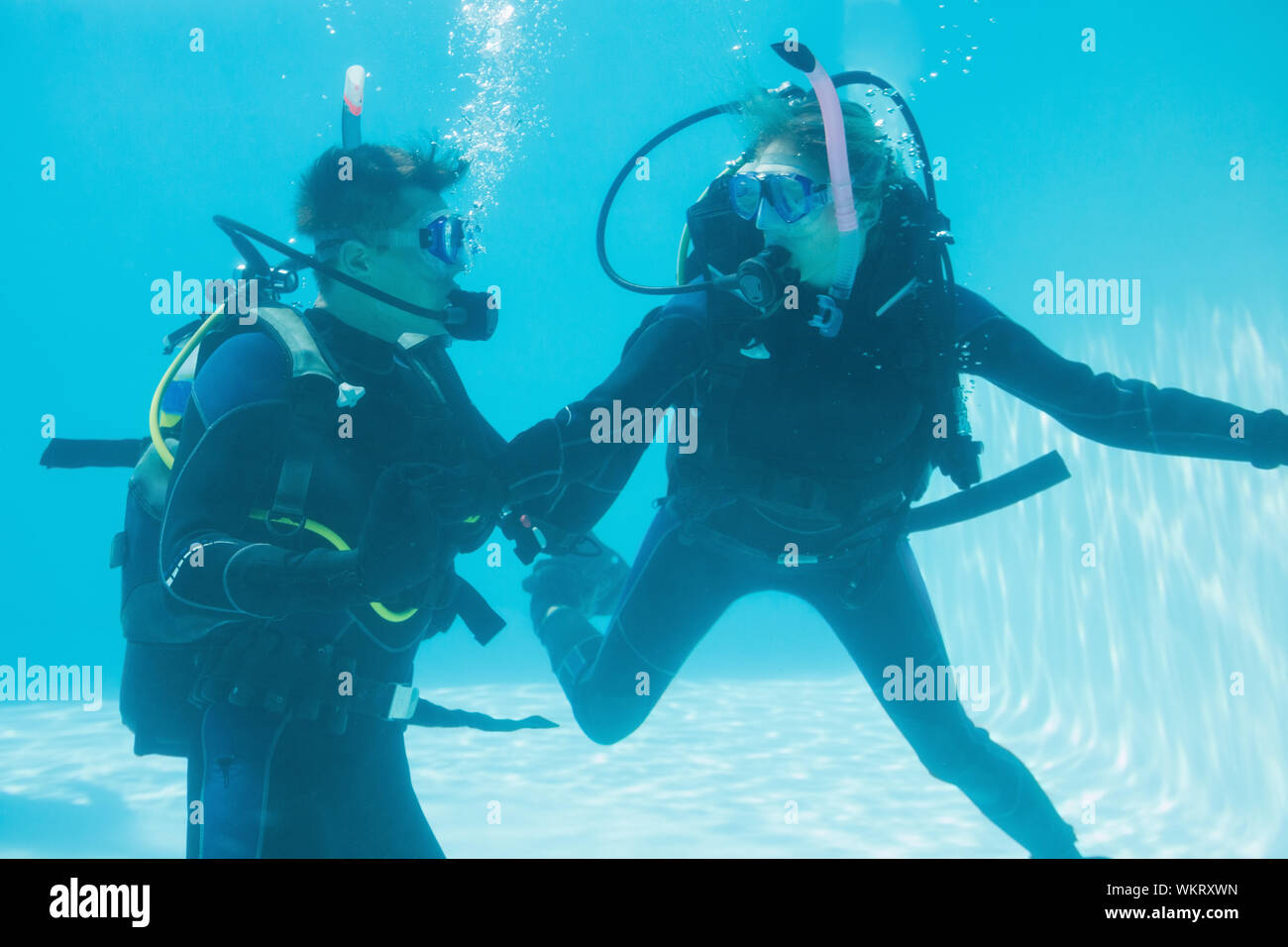 Friends on scuba training submerged in swimming pool on their holidays ...
