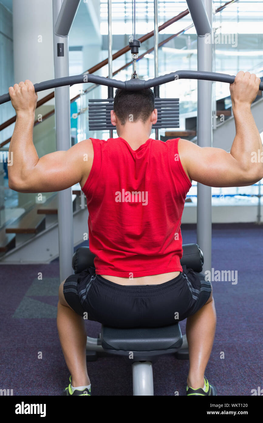 Strong bodybuilder using weight machine for arms at the gym Stock Photo ...