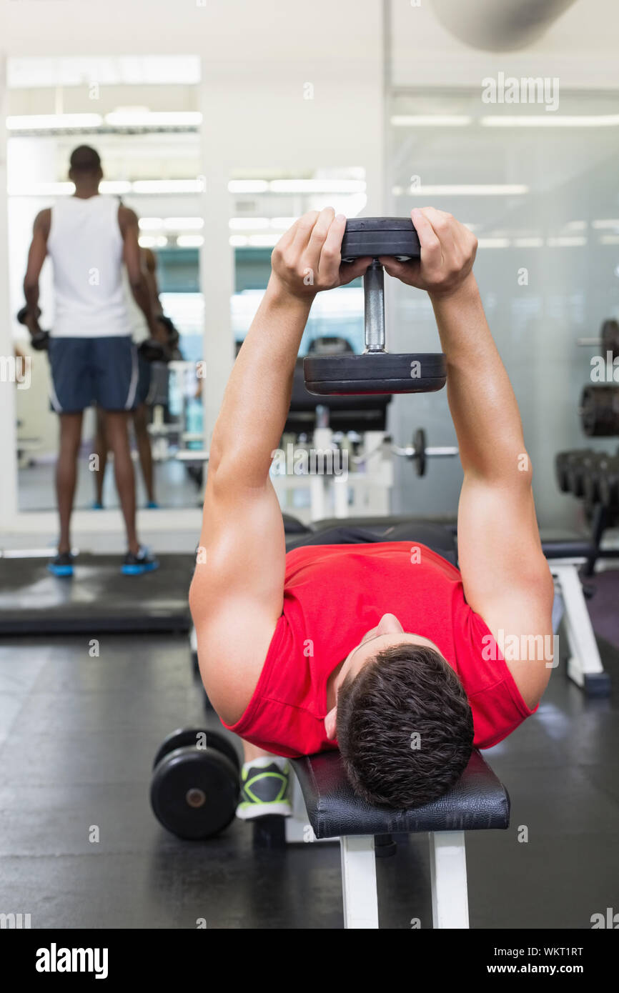 Bodybuilder lying on bench lifting heavy dumbbell at the gym Stock ...