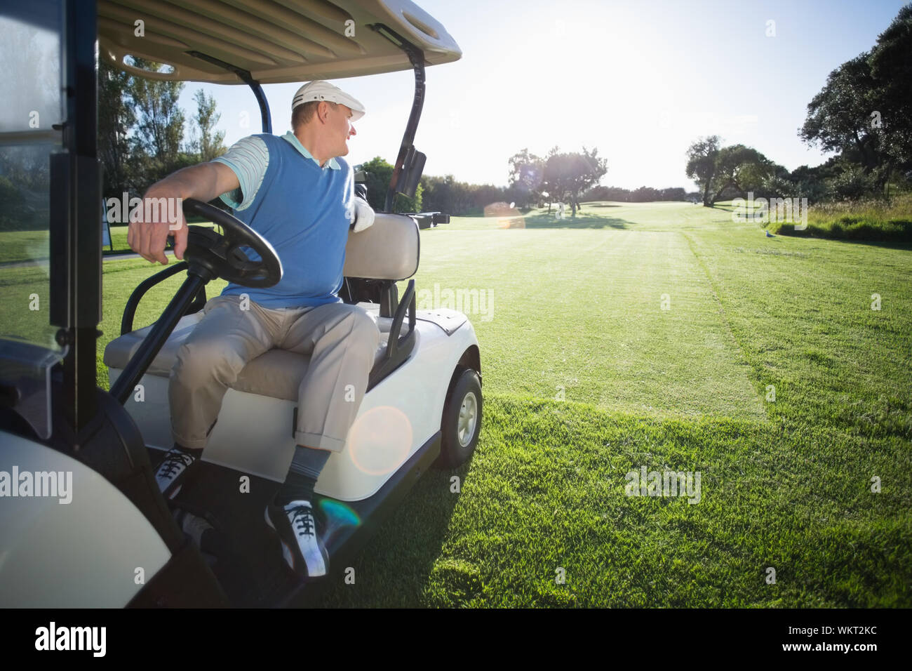 Golfer driving his golf buggy in reverse on a sunny day at the golf ...