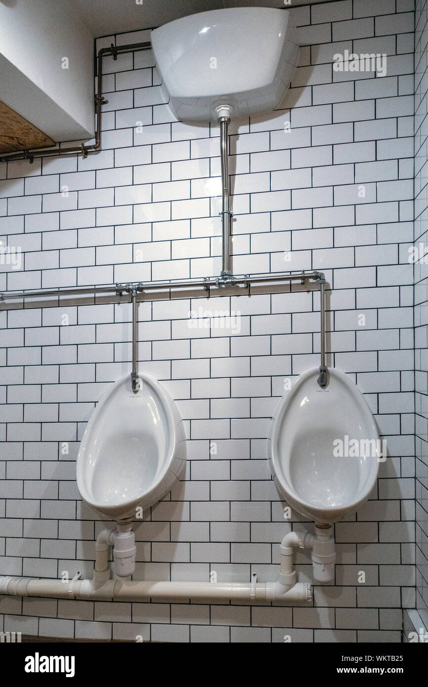 2 traditional porcelain mens urinals on a tiled restroom bathroom wall ...