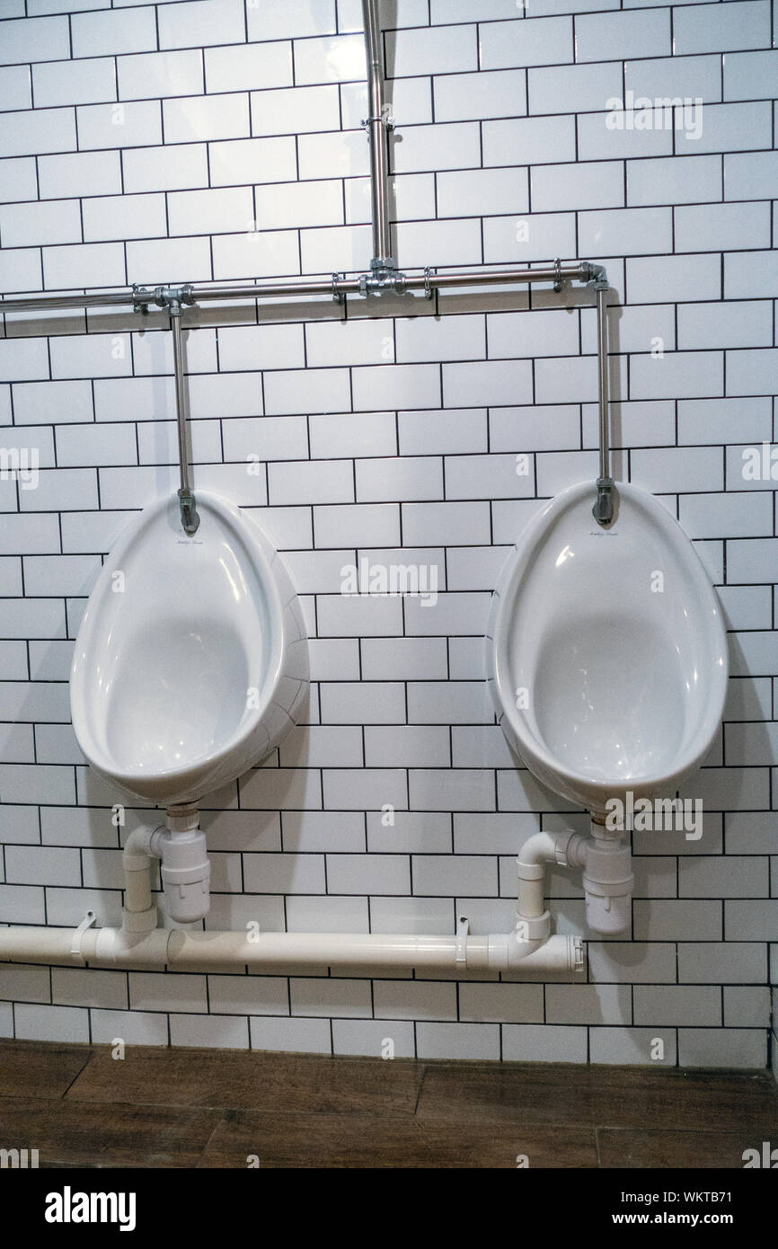 2 traditional porcelain mens urinals on a tiled restroom bathroom wall ...