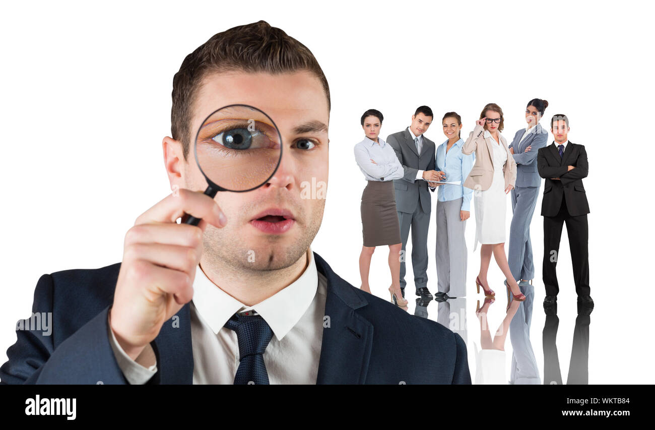 Composite image of businessman looking through magnifying glass against ...