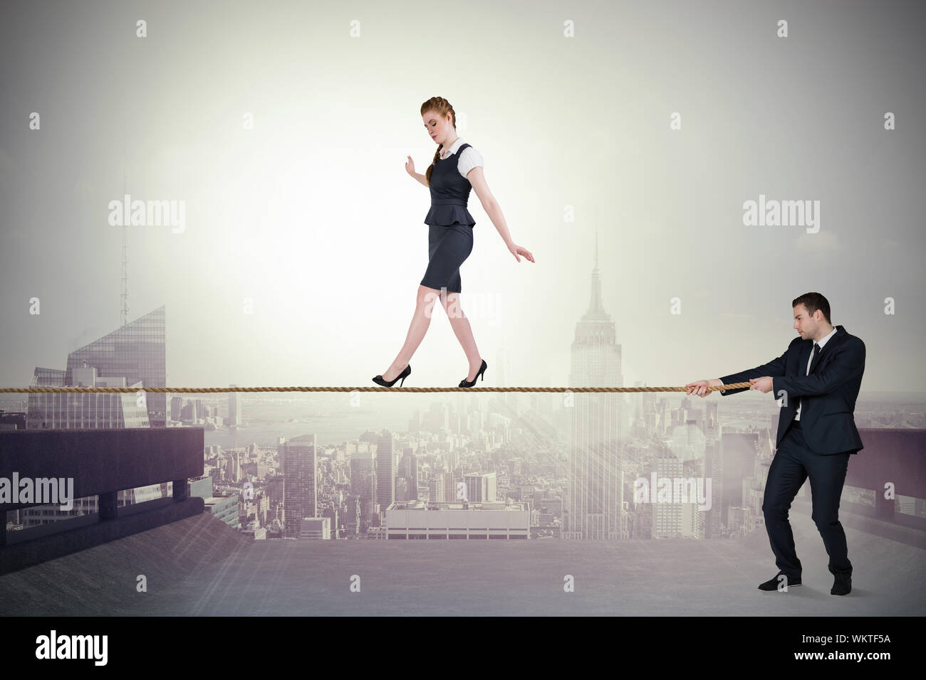 Young business man pulling a tightrope for businesswoman against ...