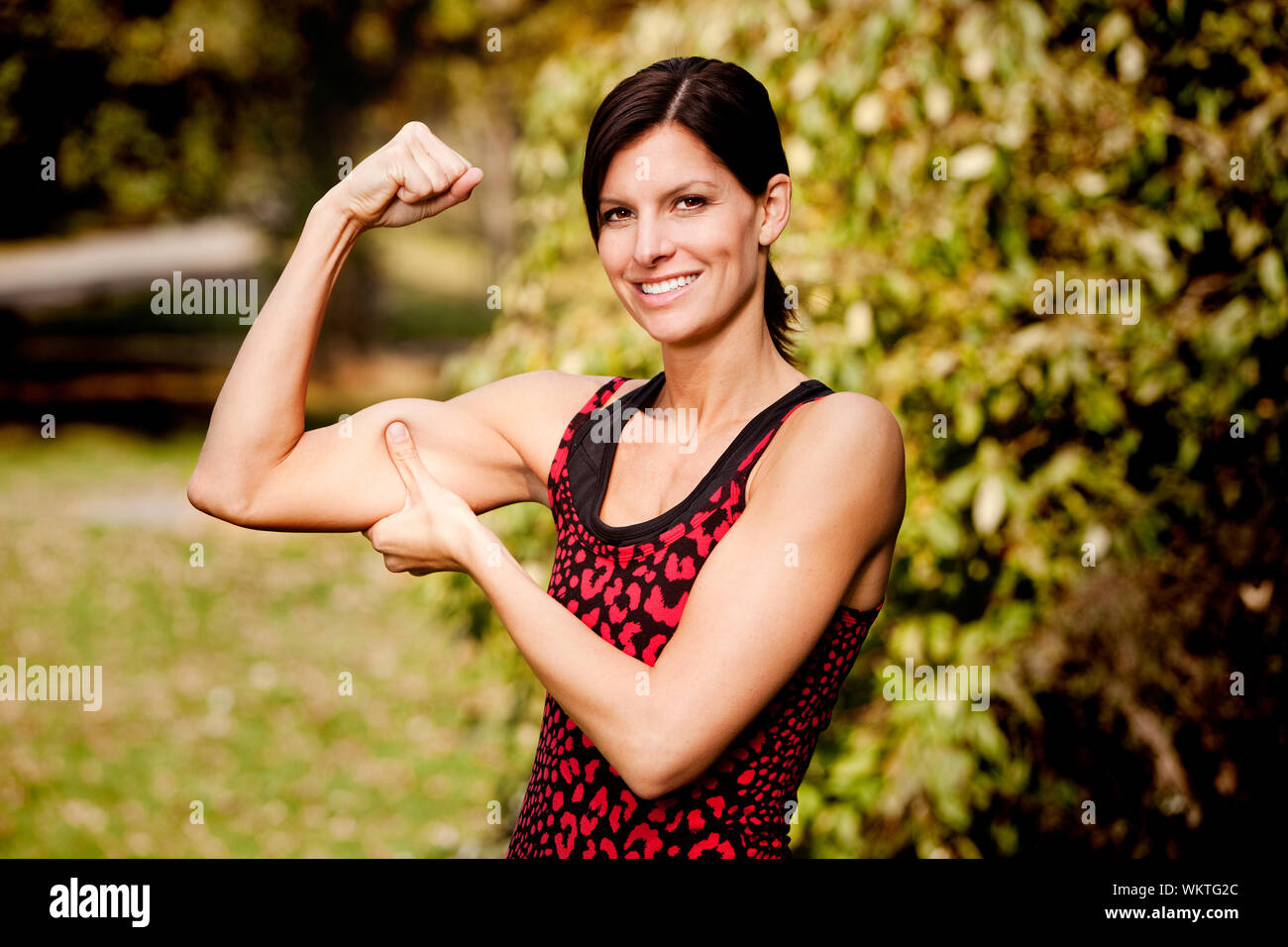 A woman flexing her biscep and making it larger Stock Photo - Alamy