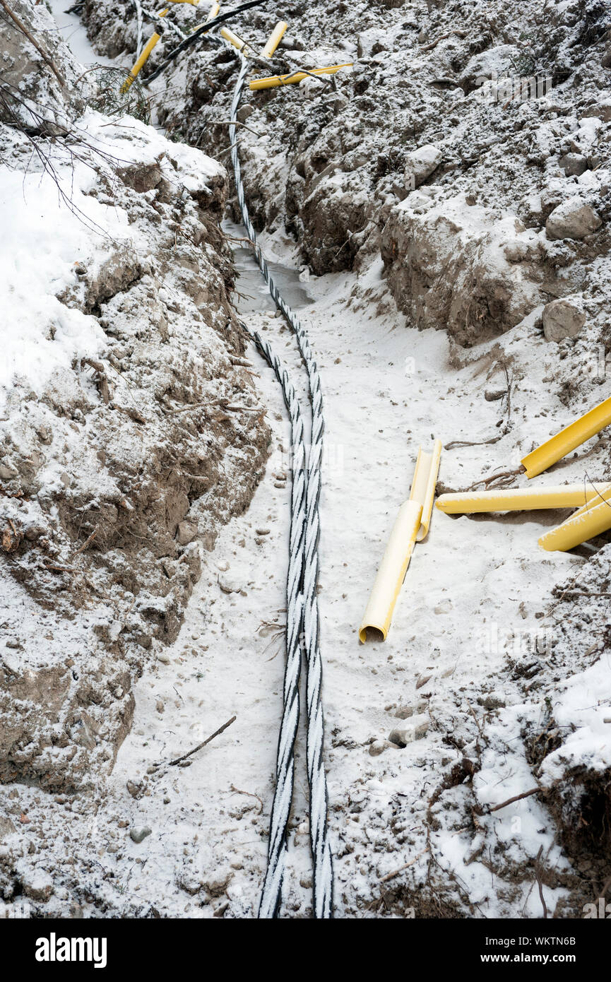 Laying a fiber optic and electricity cables in the frozen ground ...