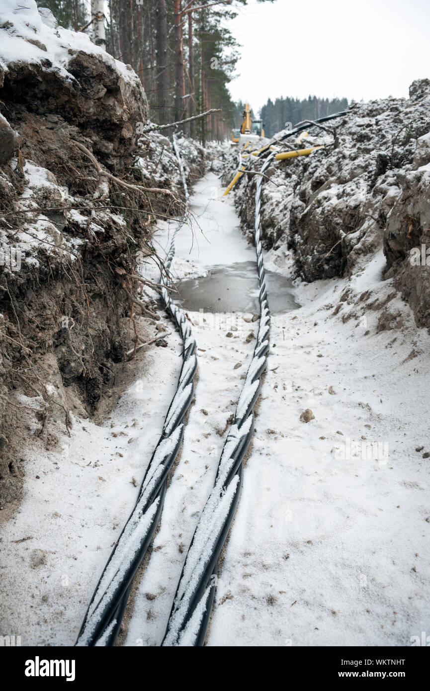 Laying a fiber optic and electricity cables in the frozen ground ...