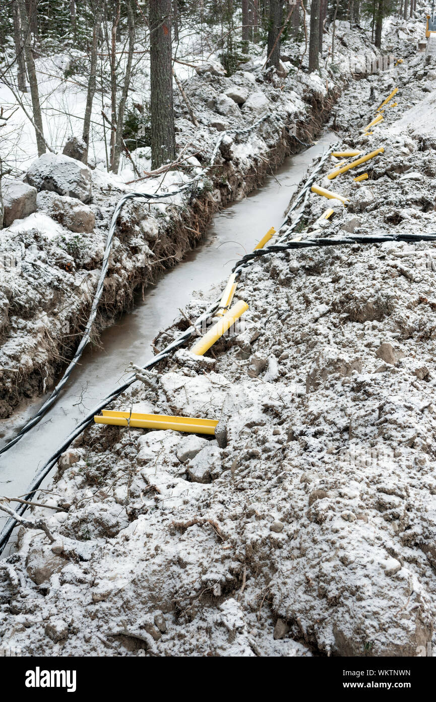 Laying a fiber optic and electricity cables in the frozen ground ...