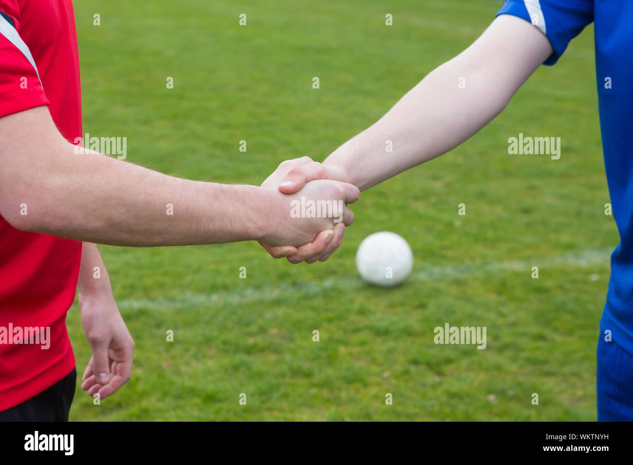 Football players in blue and red shaking hands on a clear day Stock ...