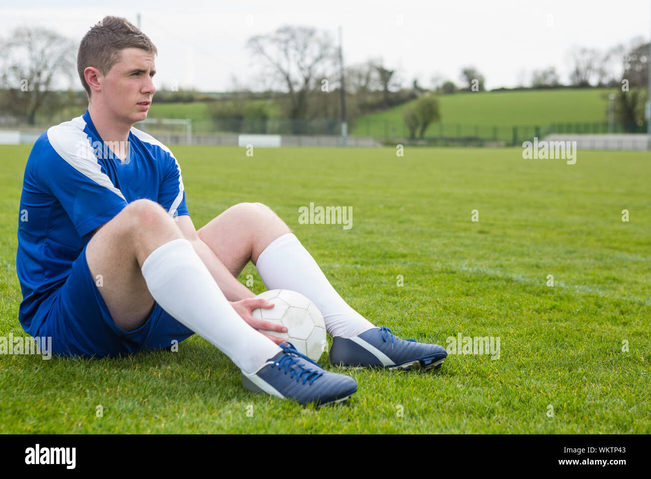 Football player in blue taking a break on the pitch on a clear day ...