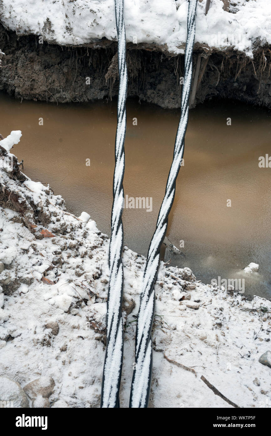 Laying a fiber optic and electricity cables in the frozen ground ...