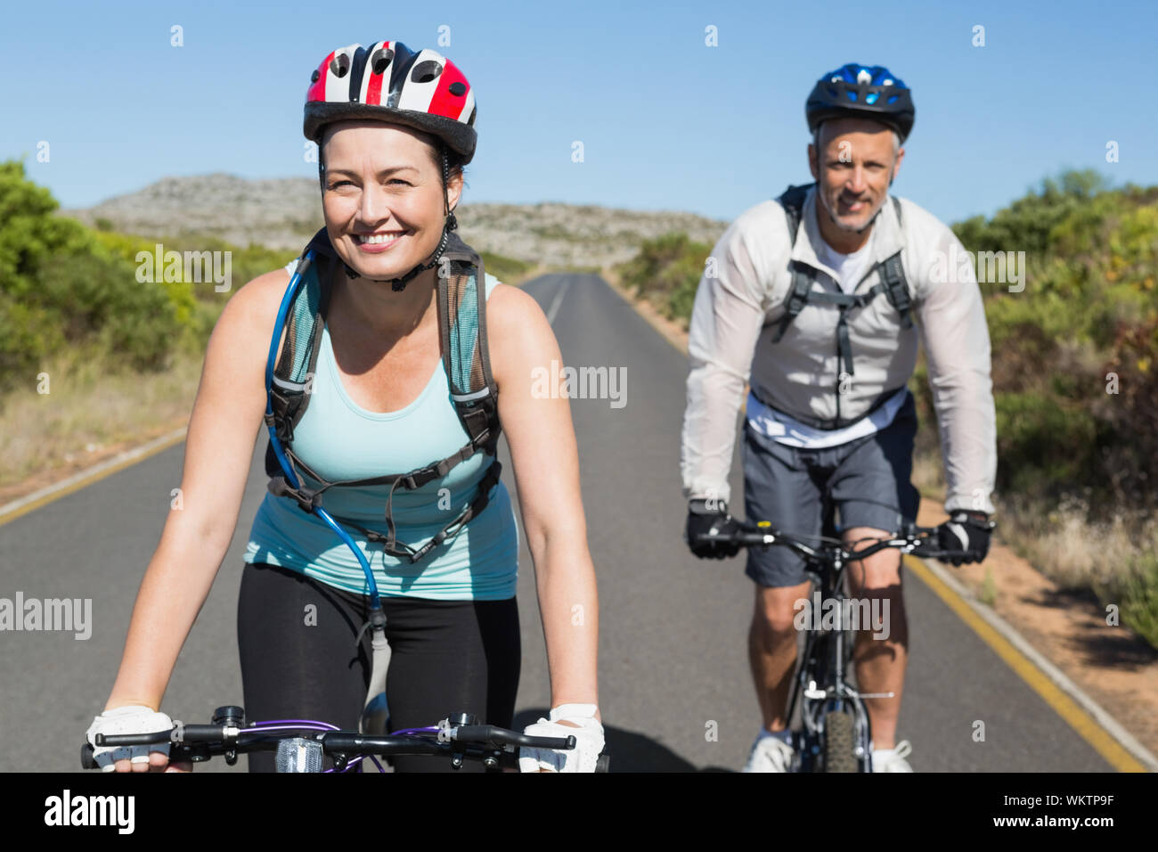 Active couple going for a bike ride in the countryside on a sunny day ...