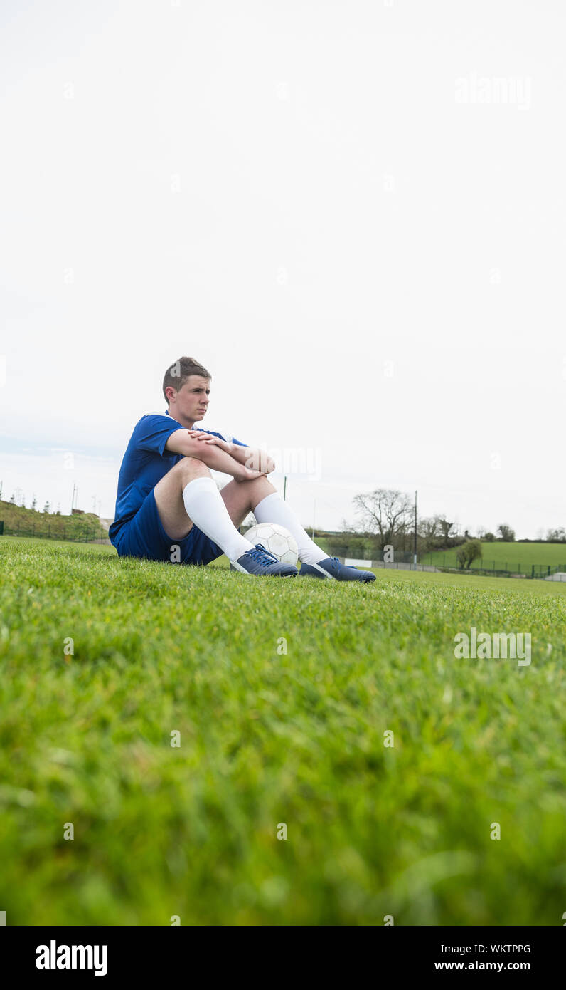Football player in blue taking a break on the pitch on a clear day ...