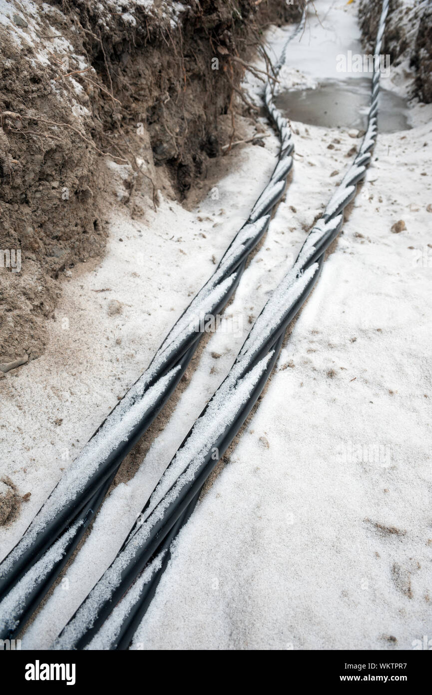 Laying a fiber optic and electricity cables in the frozen ground ...