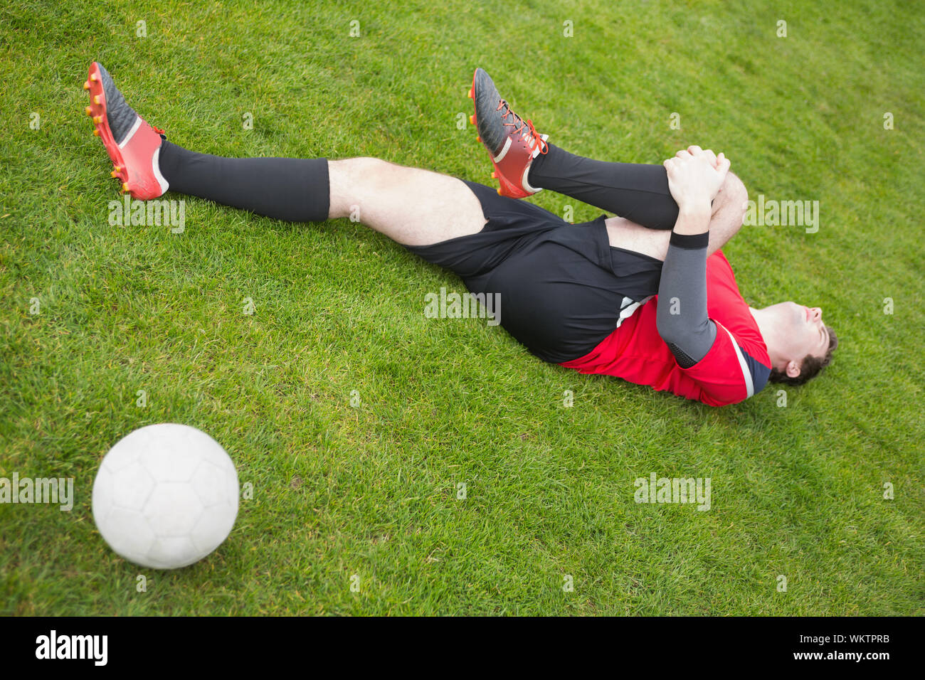Football player in red lying injured on the pitch on a clear day Stock ...