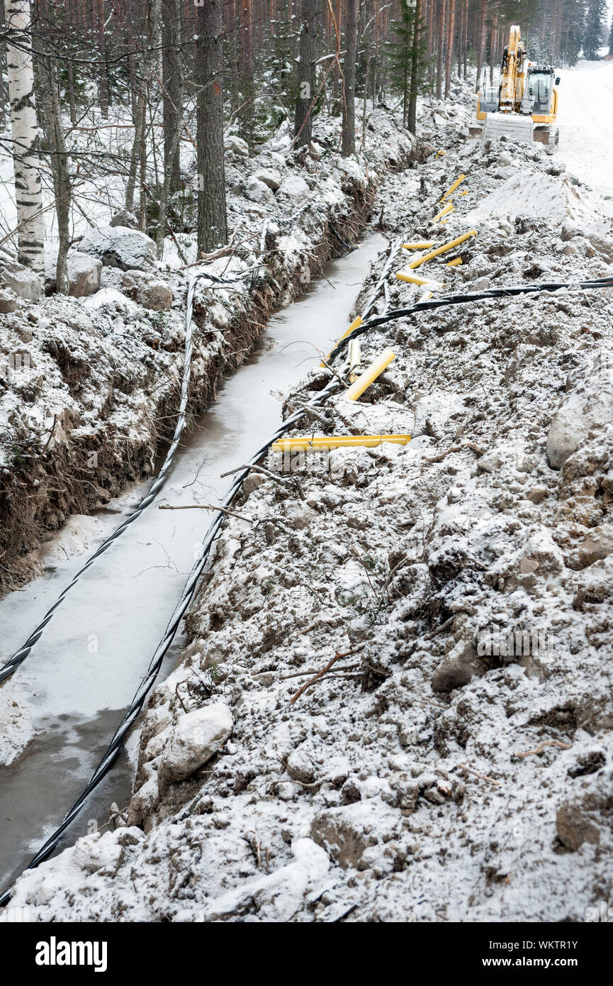 Laying a fiber optic and electricity cables in the frozen ground ...