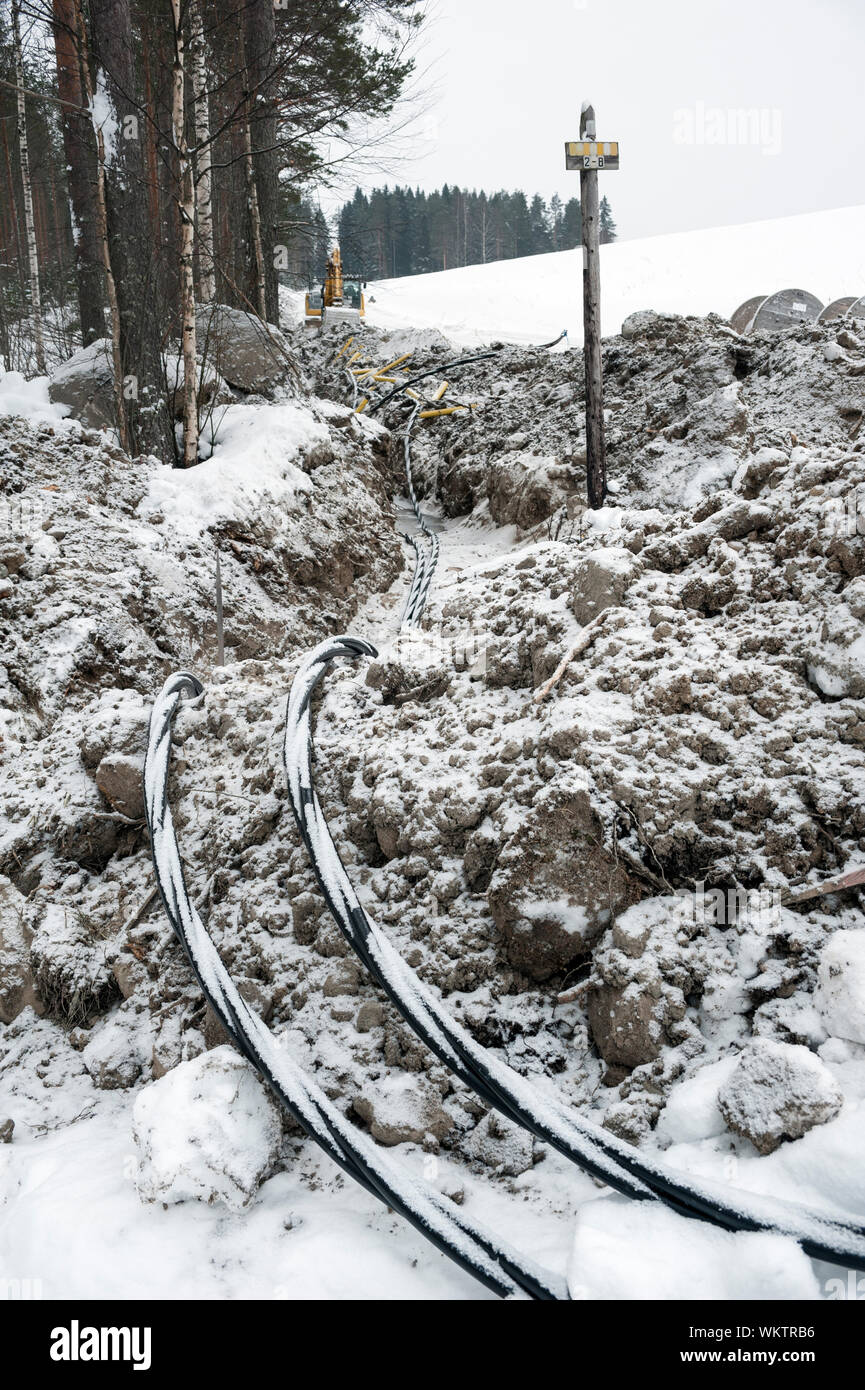 Laying a fiber optic and electricity cables in the frozen ground ...