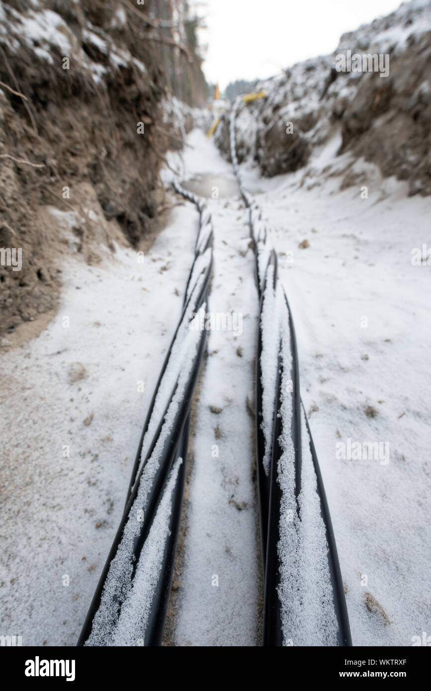 Laying a fiber optic and electricity cables in the frozen ground ...