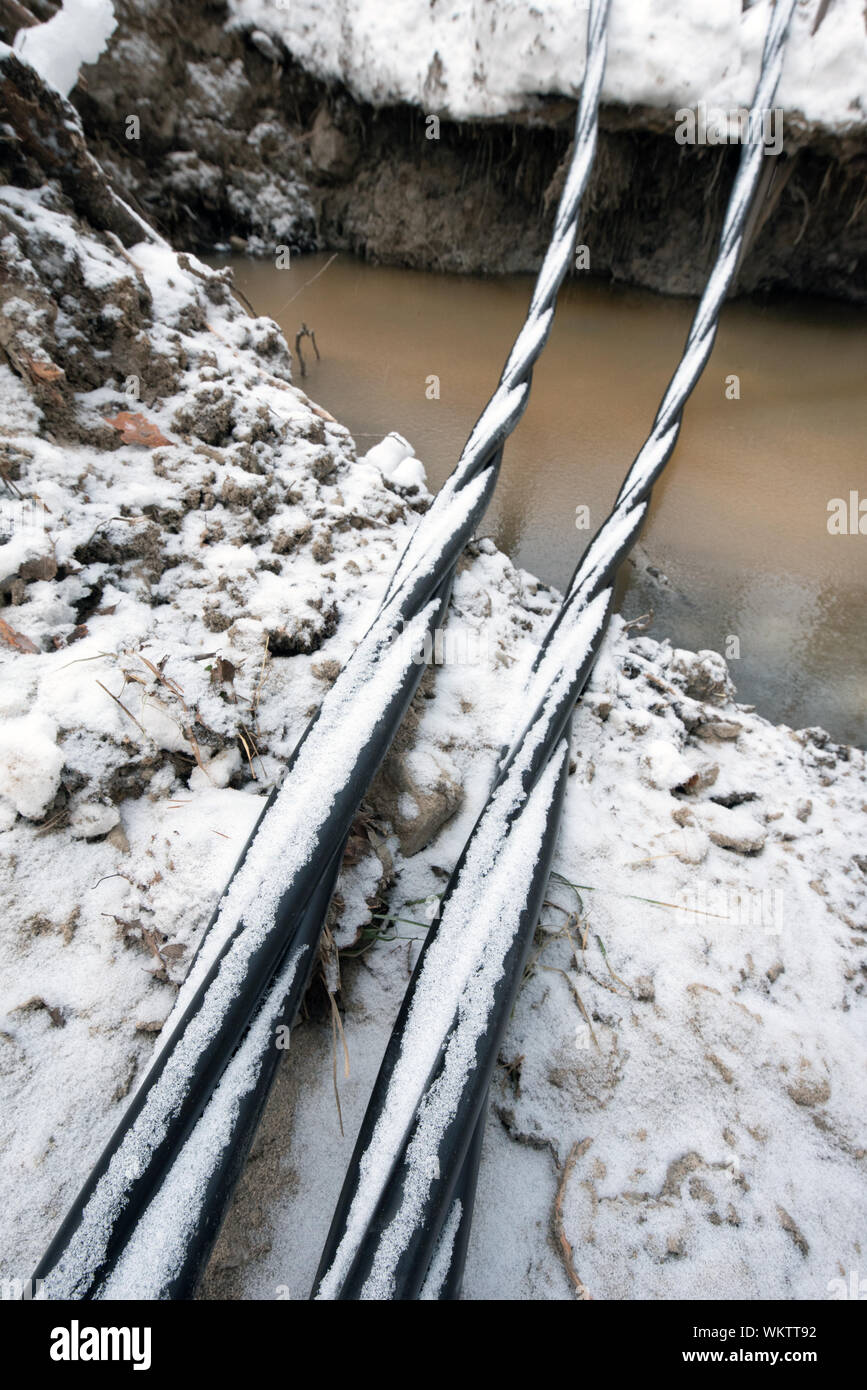 Laying a fiber optic and electricity cables in the frozen ground ...