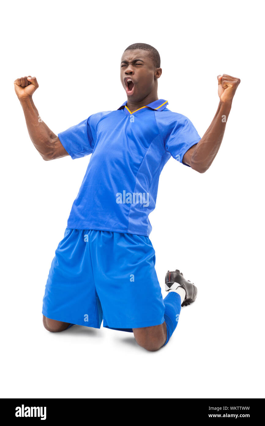Excited football player in blue cheering on his knees on white ...