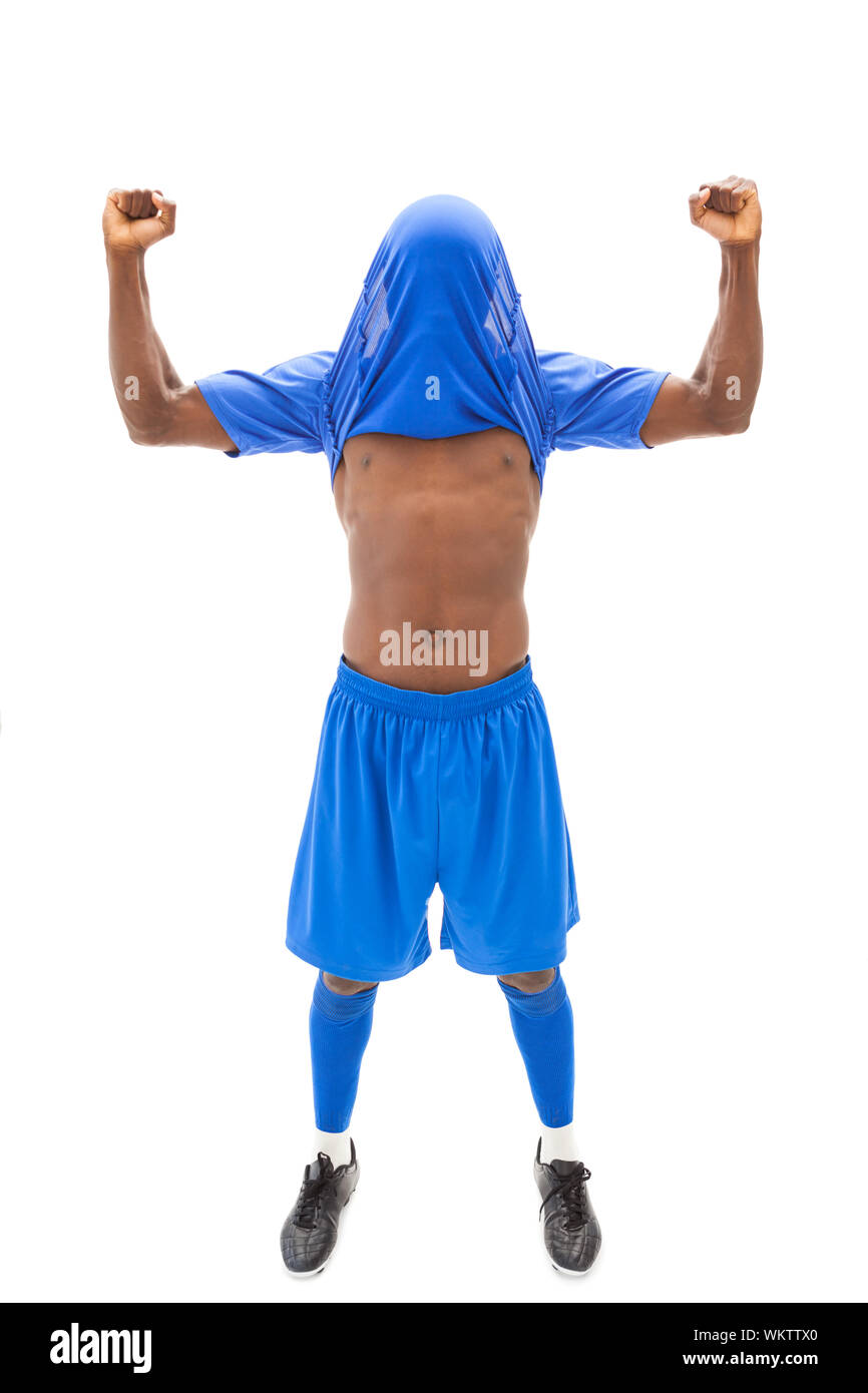 Excited football player in blue cheering with jersey over head on white ...