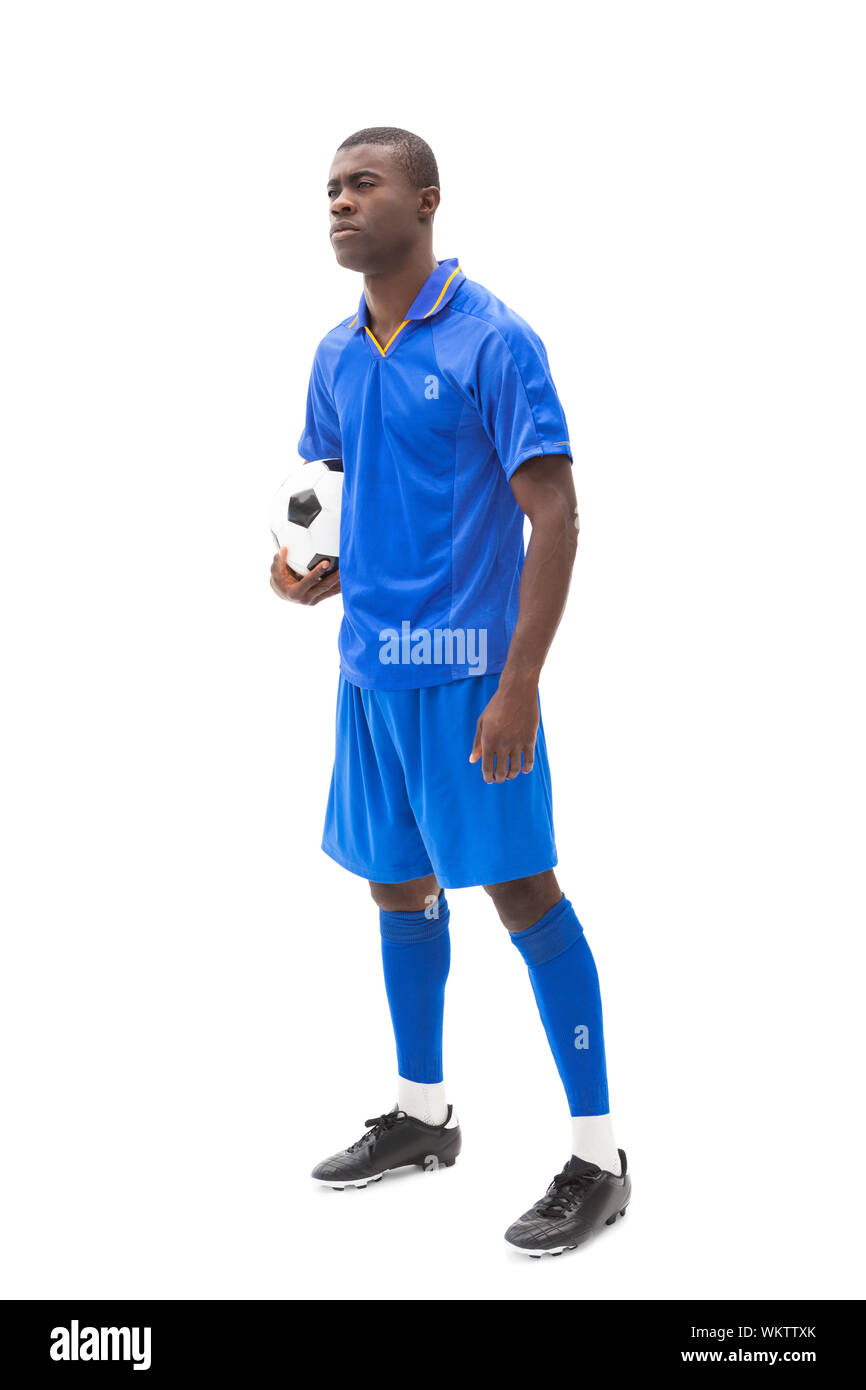 Football player in blue standing and holding ball on white background ...
