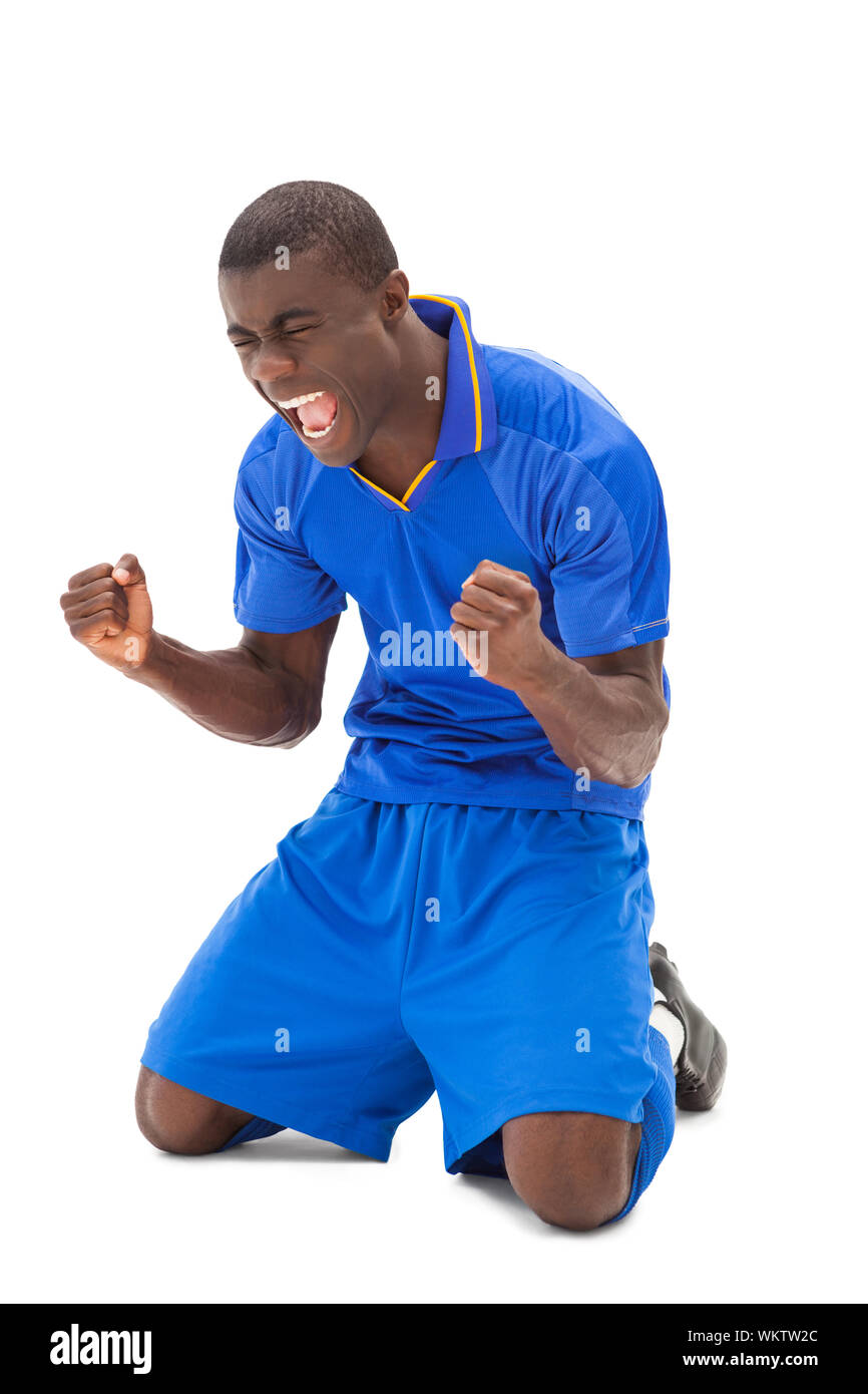 Excited football player in blue cheering on his knees on white ...