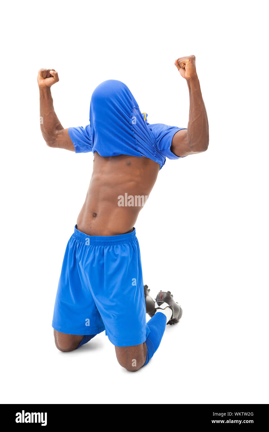 Excited football player in blue cheering on his knees on white ...