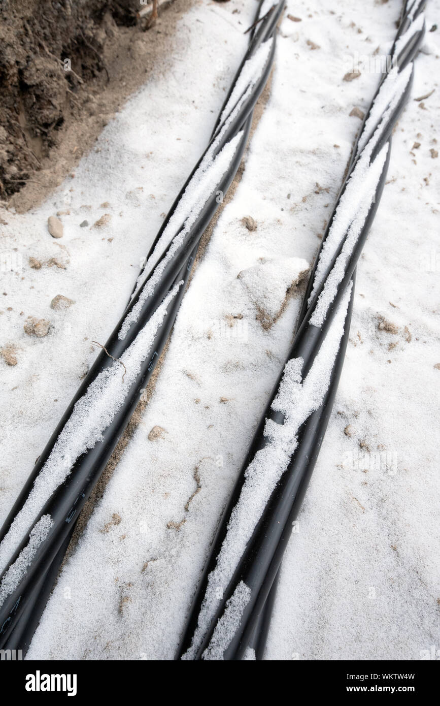 Laying a fiber optic and electricity cables in the frozen ground ...