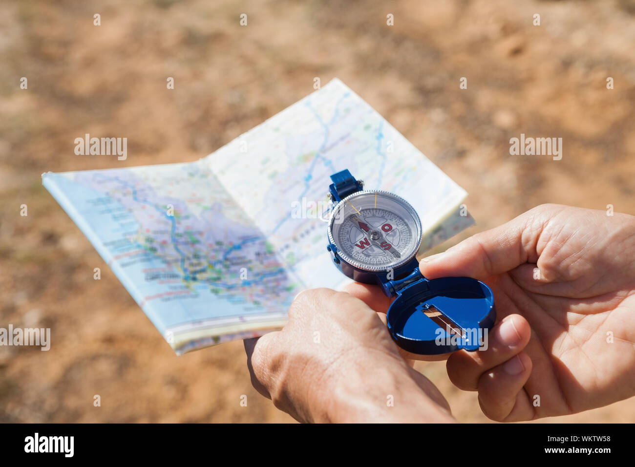 Hiker holding his compass and map in the countryside on a sunny day ...