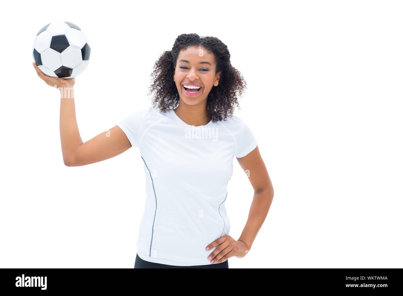 Pretty football fan in white smiling at camera holding ball on white ...