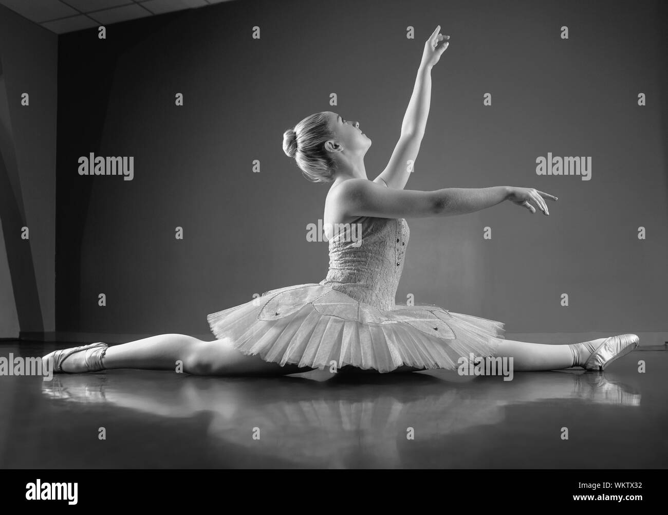 Graceful ballerina sitting with legs stretched out in the ballet studio ...