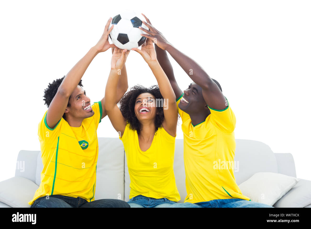 Happy football fans in yellow sitting on couch with ball on white ...