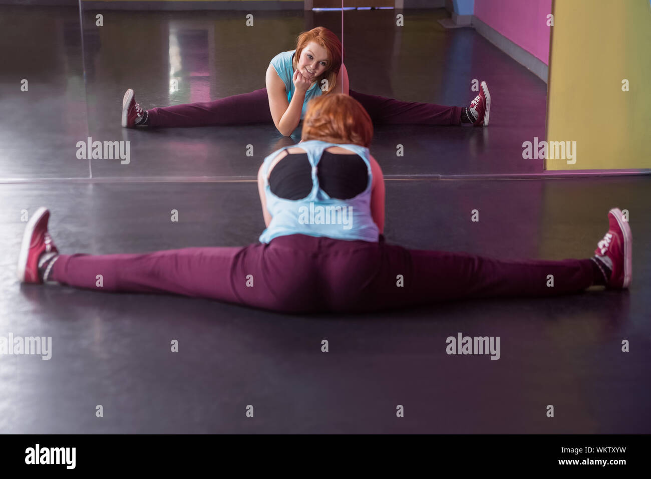 Pretty break dancer doing the splits looking in mirror in the dance ...