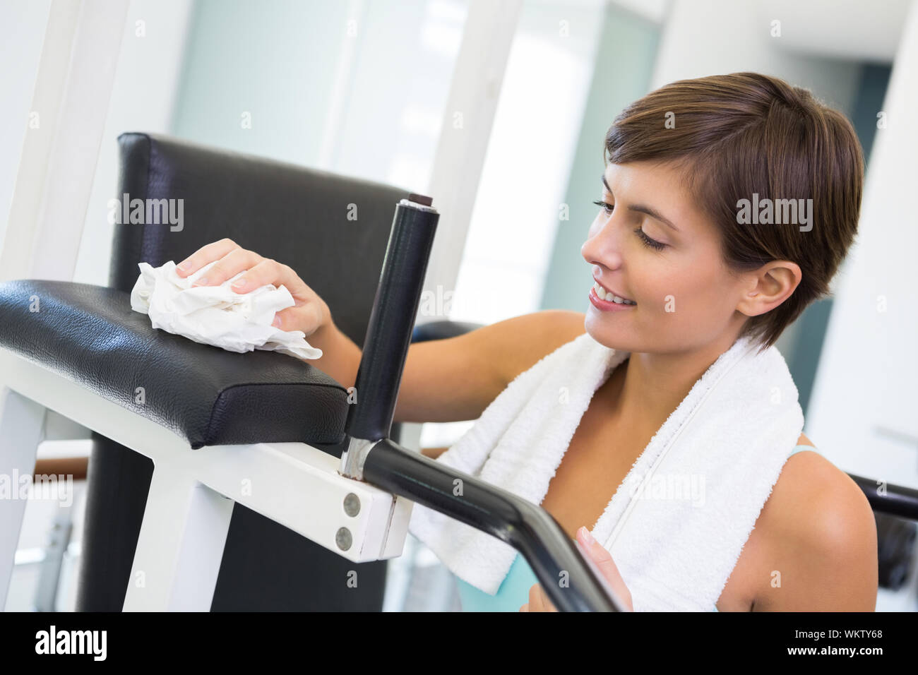 Fit brunette wiping down bench at the gym Stock Photo - Alamy