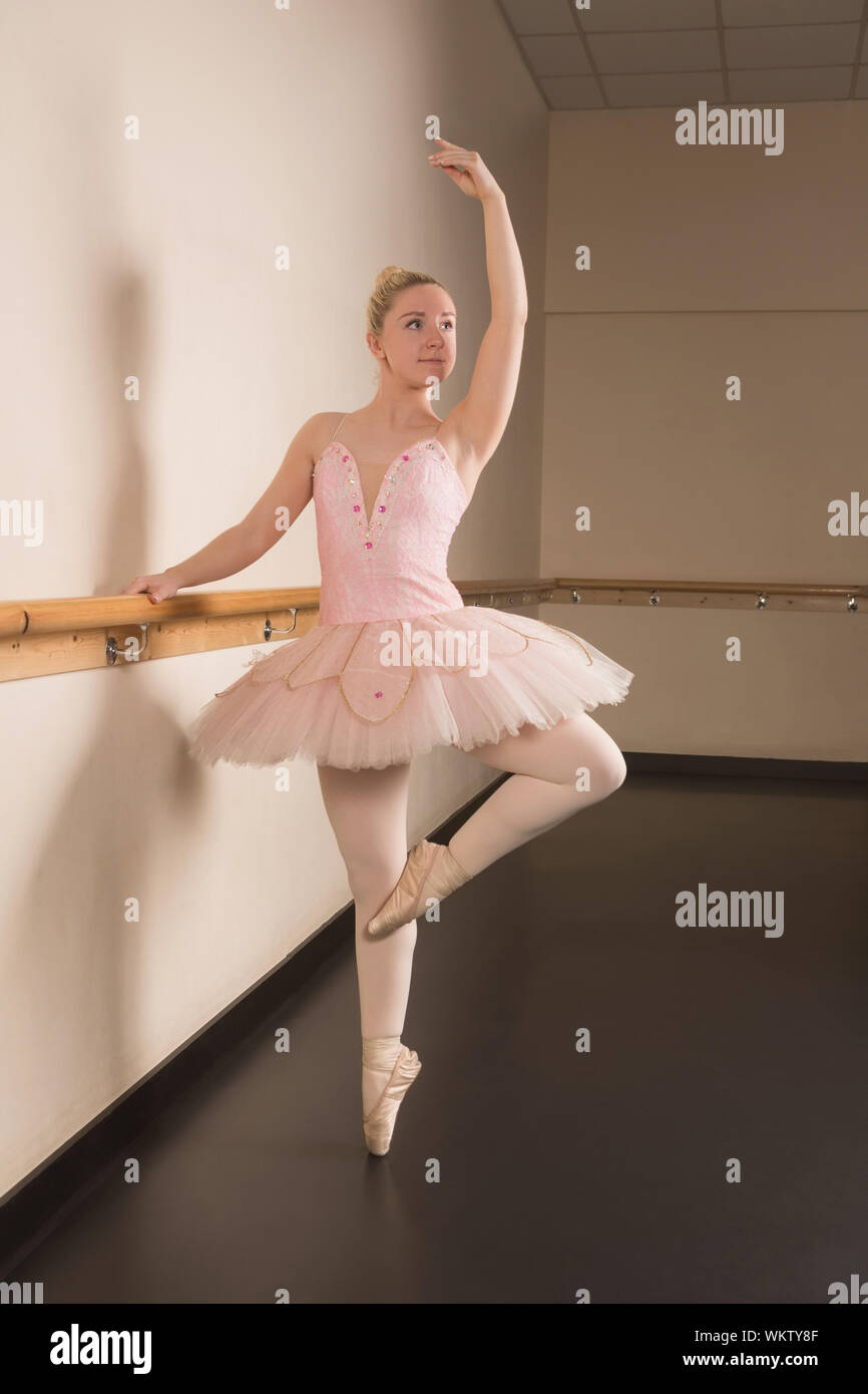 Beautiful ballerina standing en pointe holding barre in the dance ...