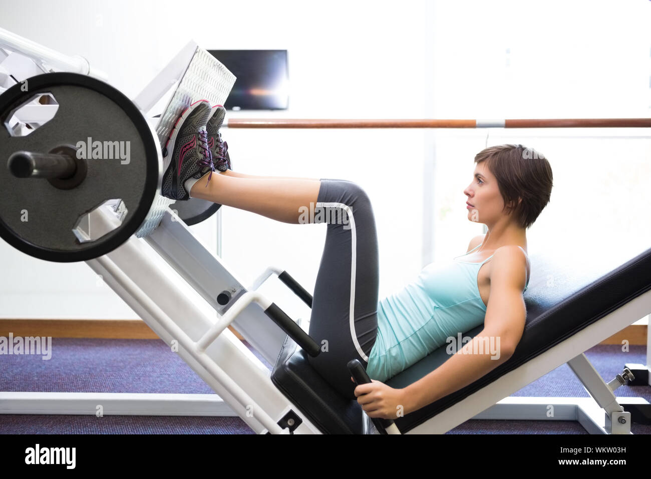 Fit brunette using weights machine for legs at the gym Stock Photo - Alamy
