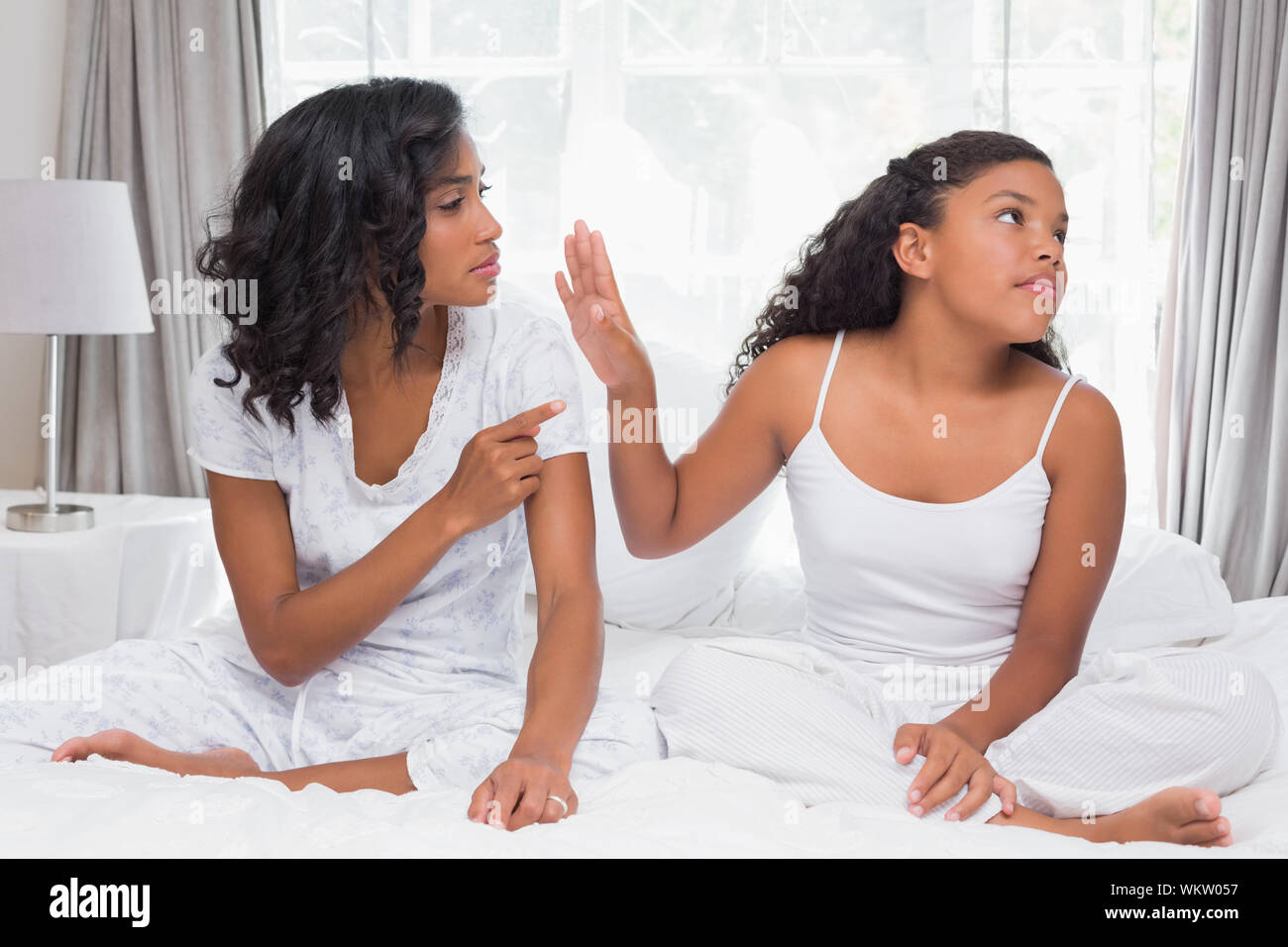 Mother And Daughter Having An Argument On Bed At Home In Bedroom Stock