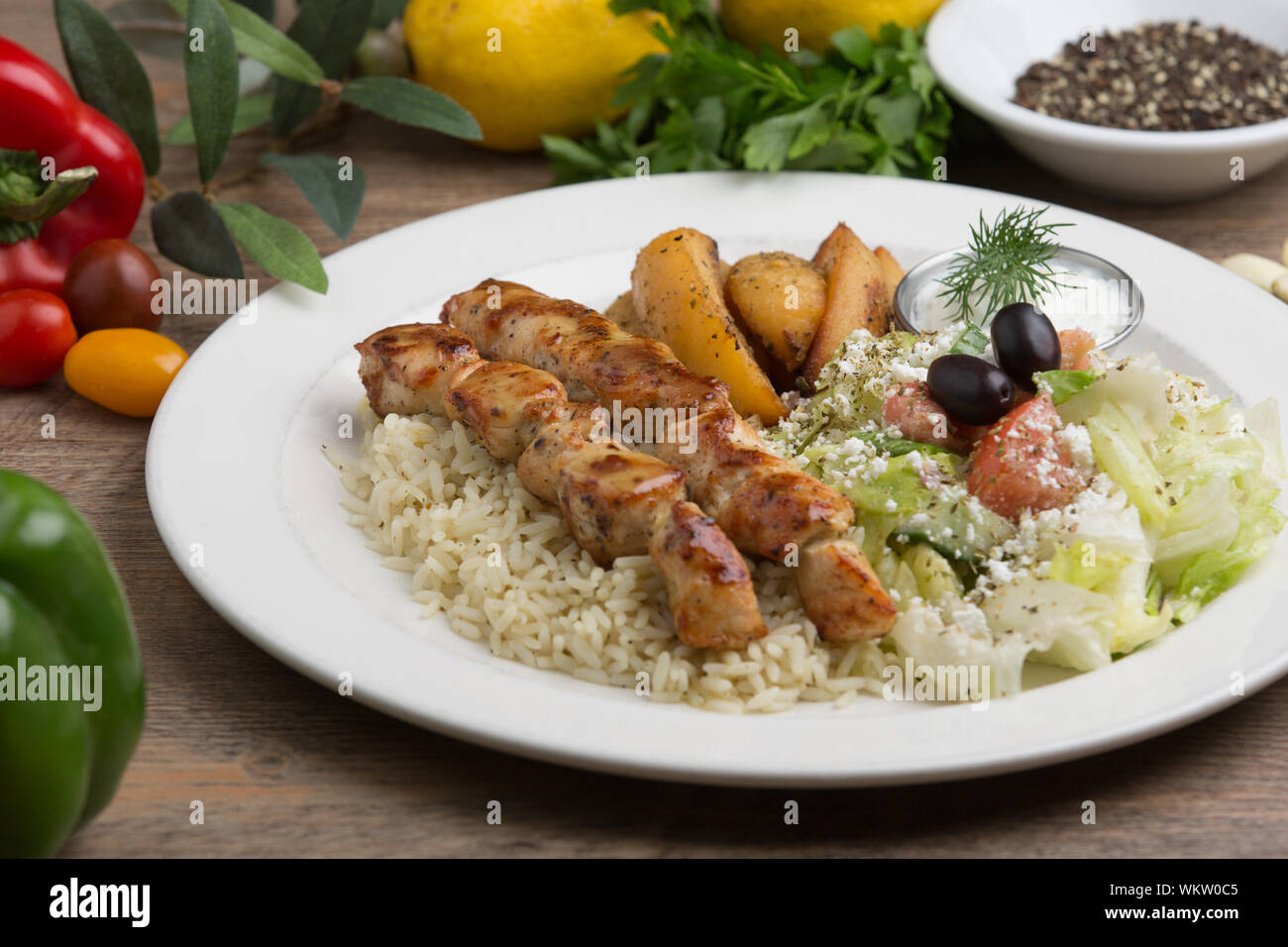 greek chicken kabobs on rice with potatoes. served on White plates ...